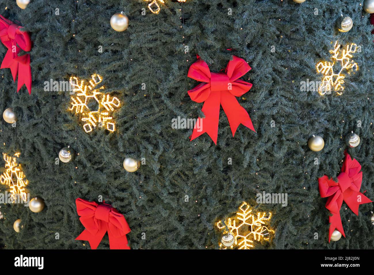 Christmas artificial fir tree with red bows, glowing snowflakes and ...