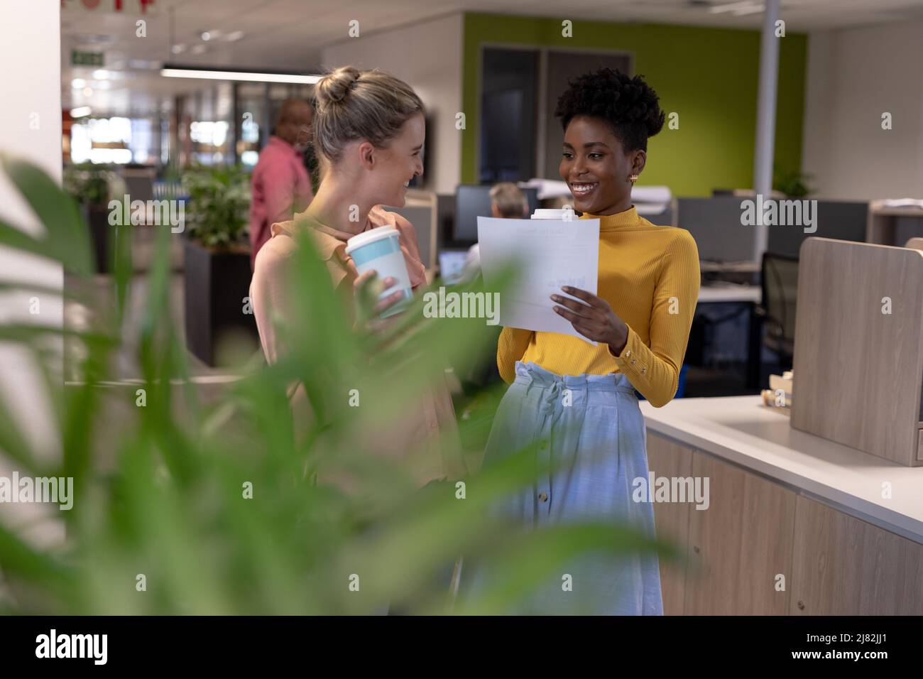 Happy multiracial female advisors with drink and document working ...