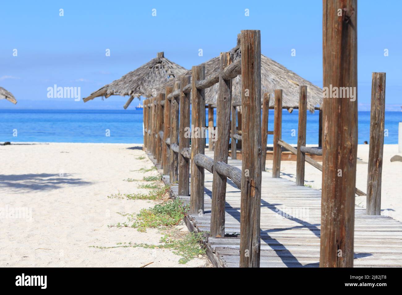 Wooden walkway on the beach with umbrellas in the background Stock ...