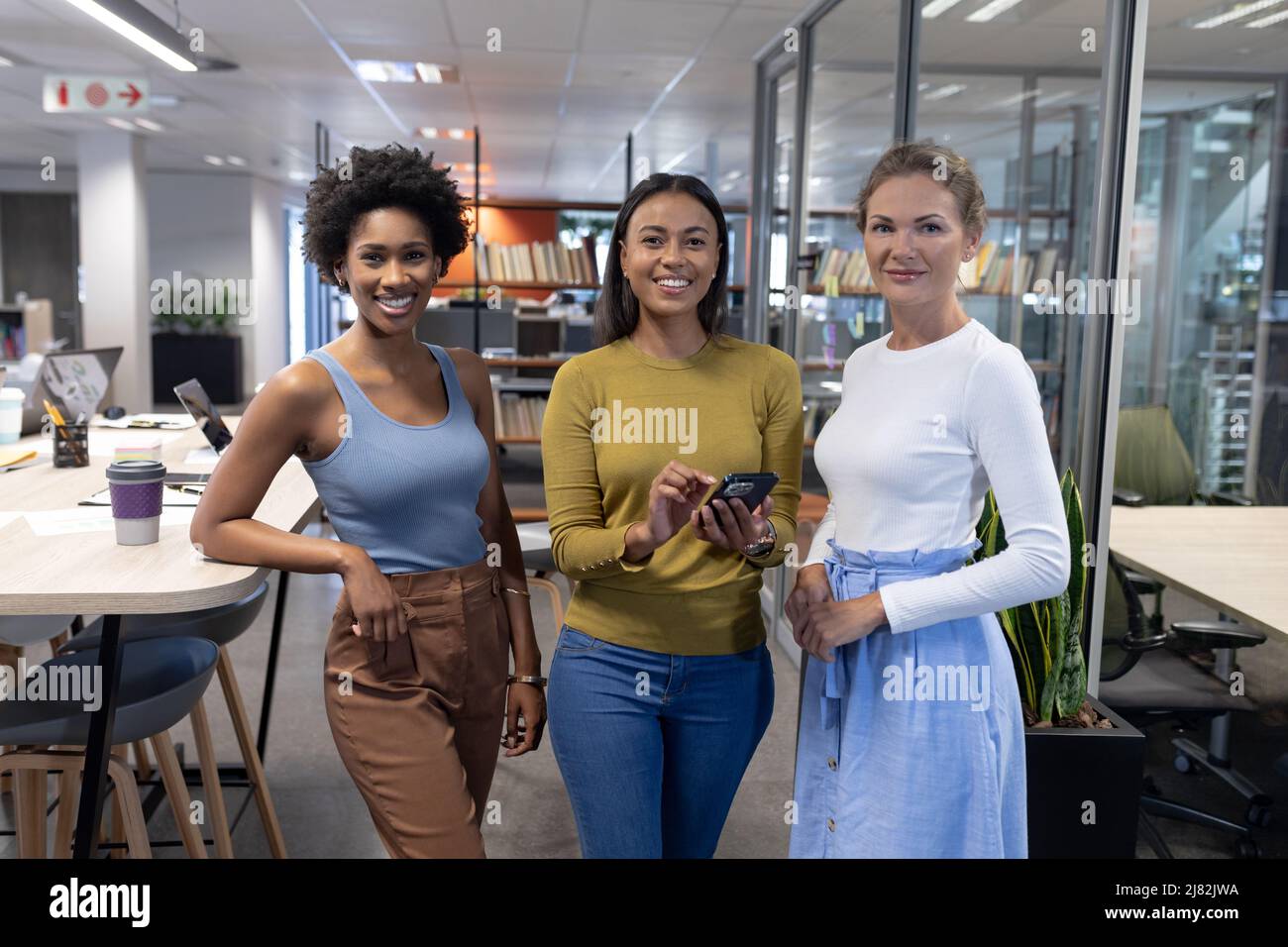 Portrait of smiling female multiracial colleagues standing together in ...