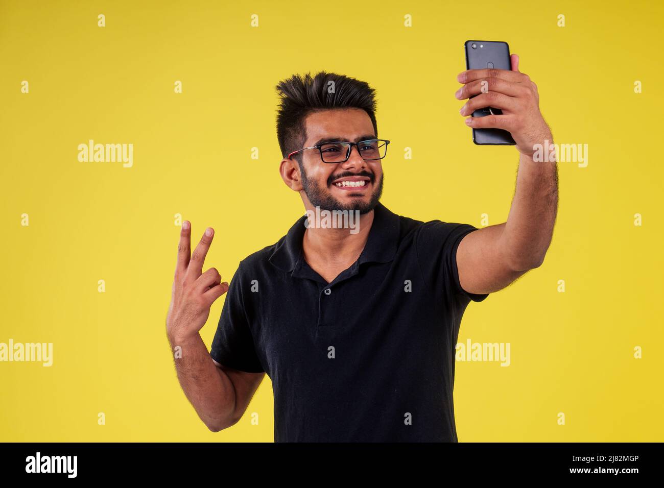 smiling handsome india man photographing selfie in studio yellow ...