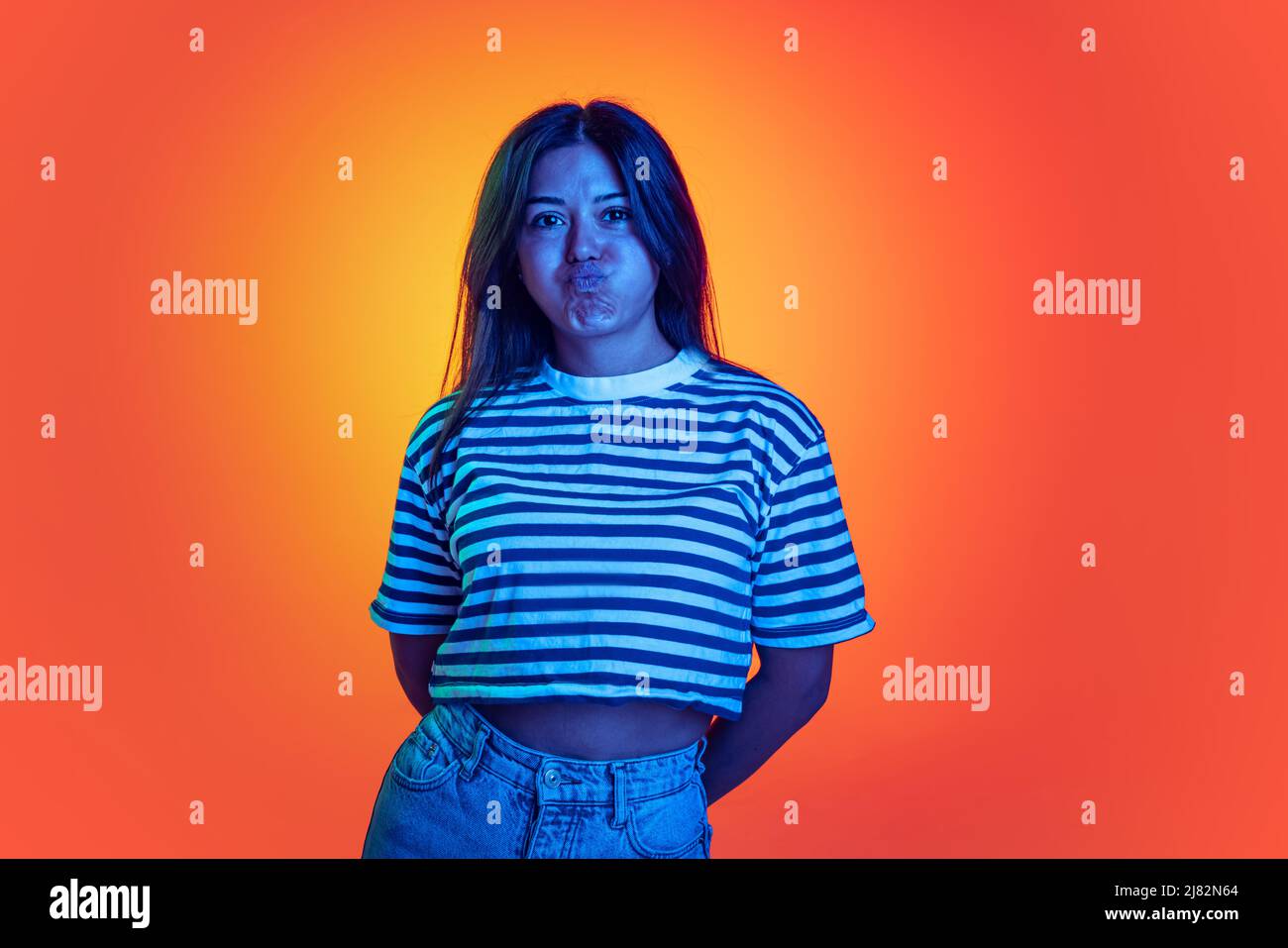 Young emotive girl making funny face, blowing cheeks, posing isolated ...