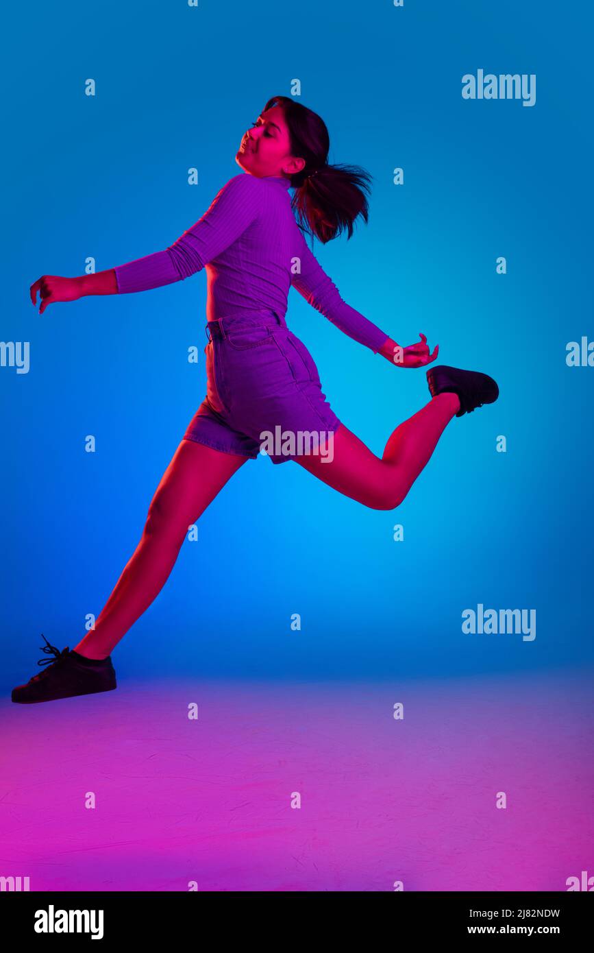 Full-length portrait of young girl cheerfully jumping isolated over ...