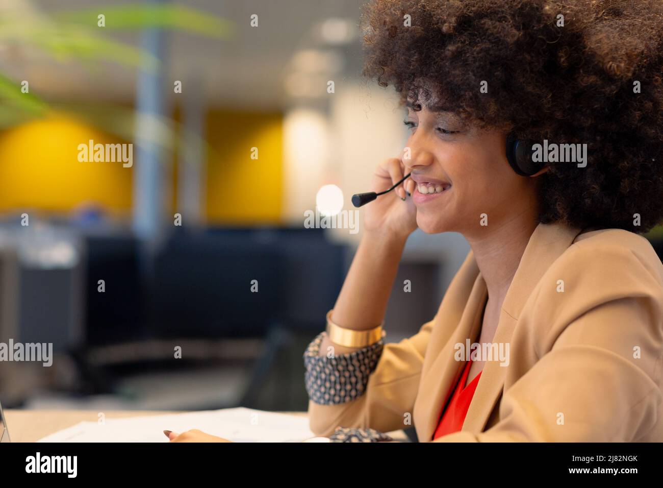 Smiling young african american female telecaller talking through ...