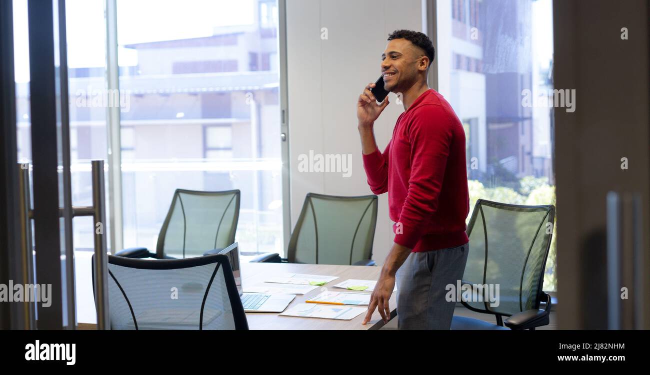 Happy hispanic male advisor talking on smartphone in boardroom during ...