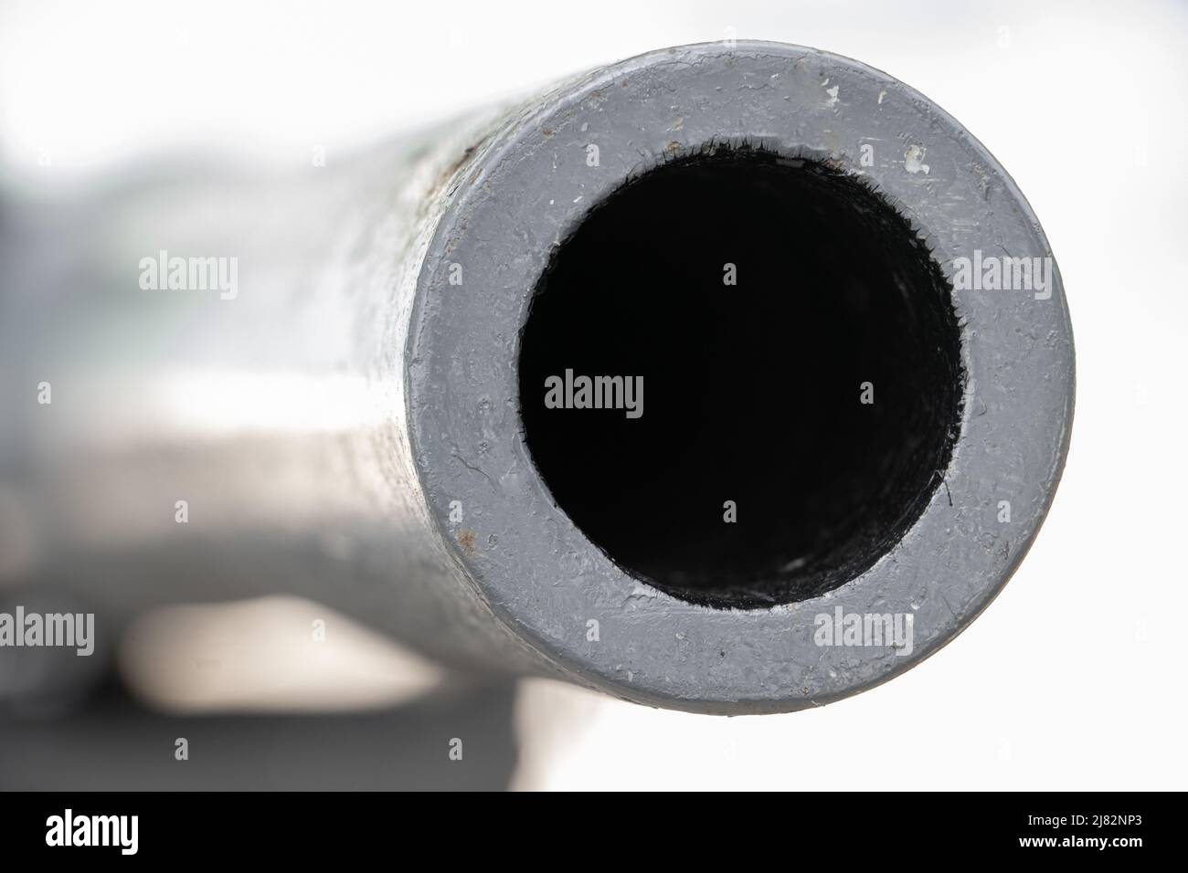 The barrel of the cannon aims front into a camera, on a white ...