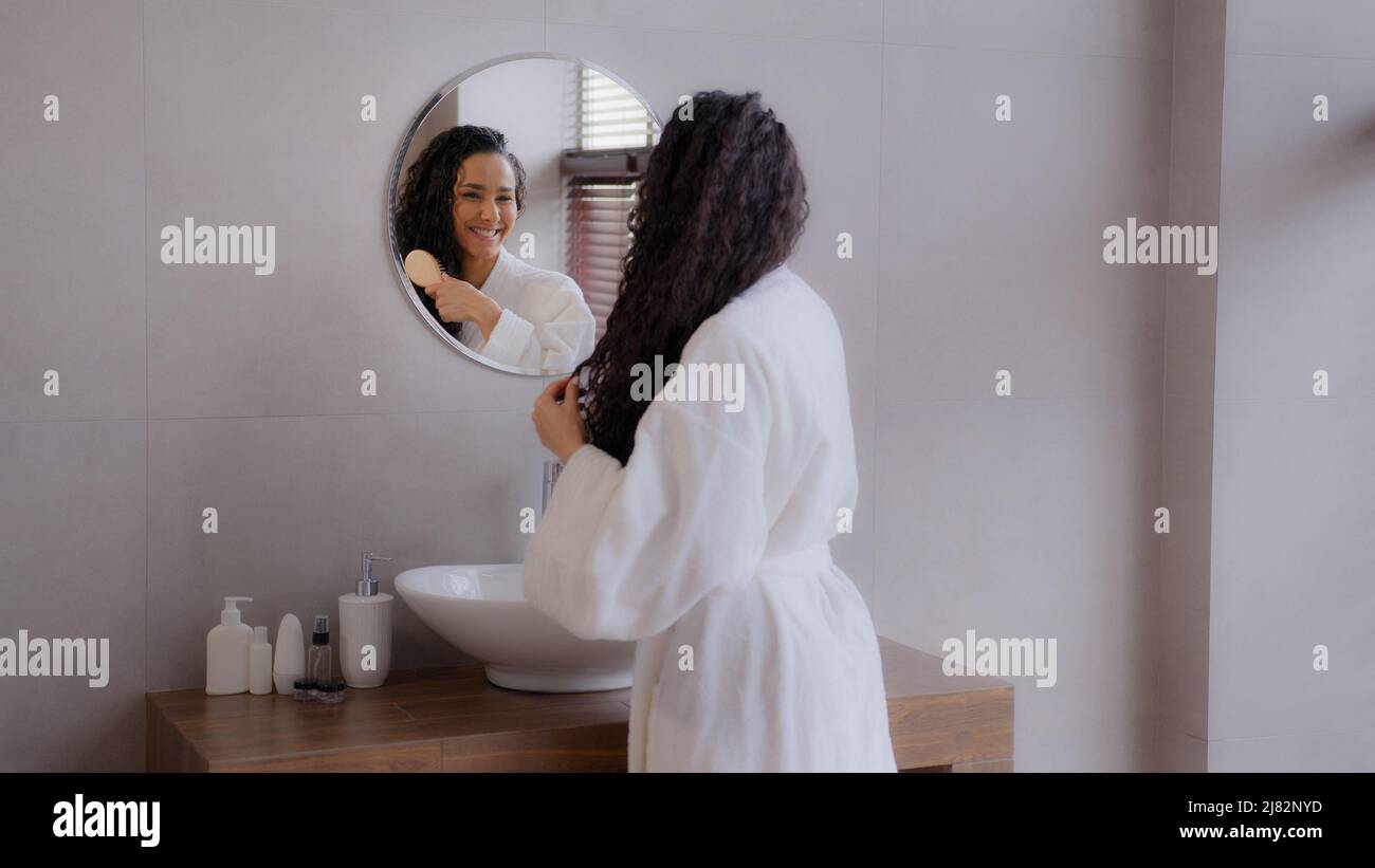 Young Happy Woman Standing In Bathroom Looking In Mirror Touching Face