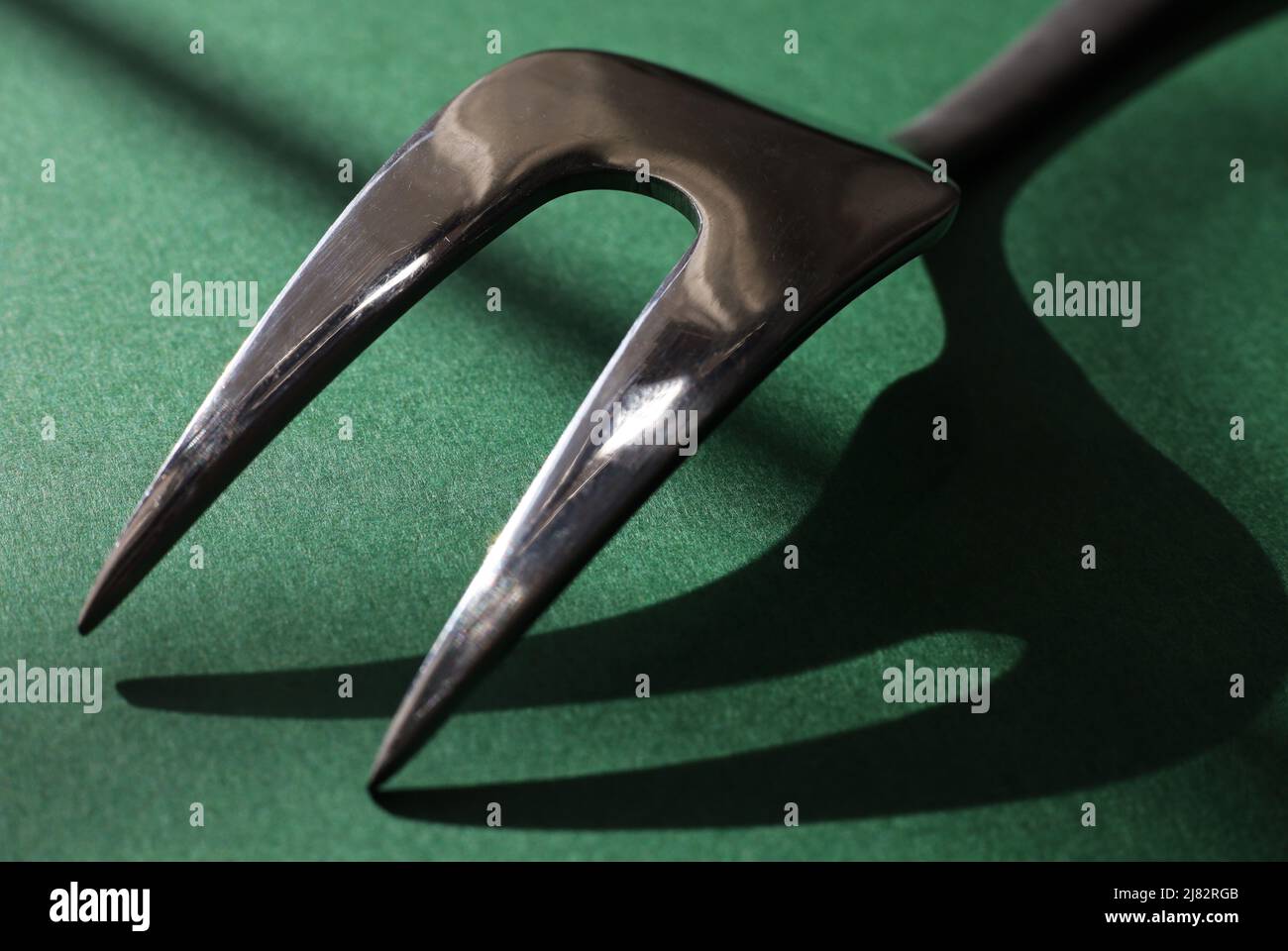 metal fork with reflection on green background Stock Photo - Alamy