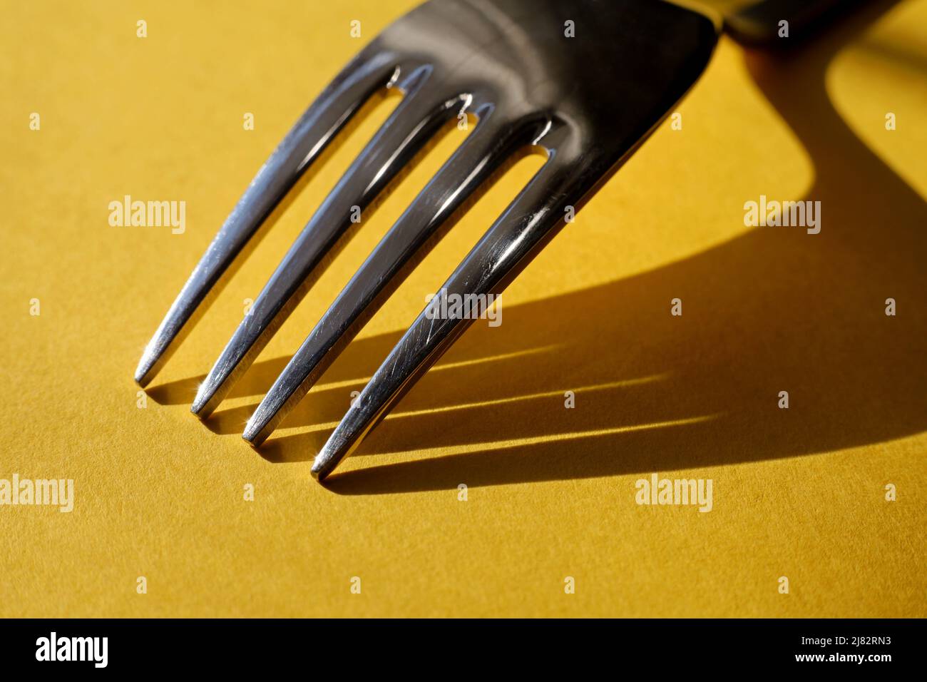 metal fork with reflection on yellow background Stock Photo - Alamy