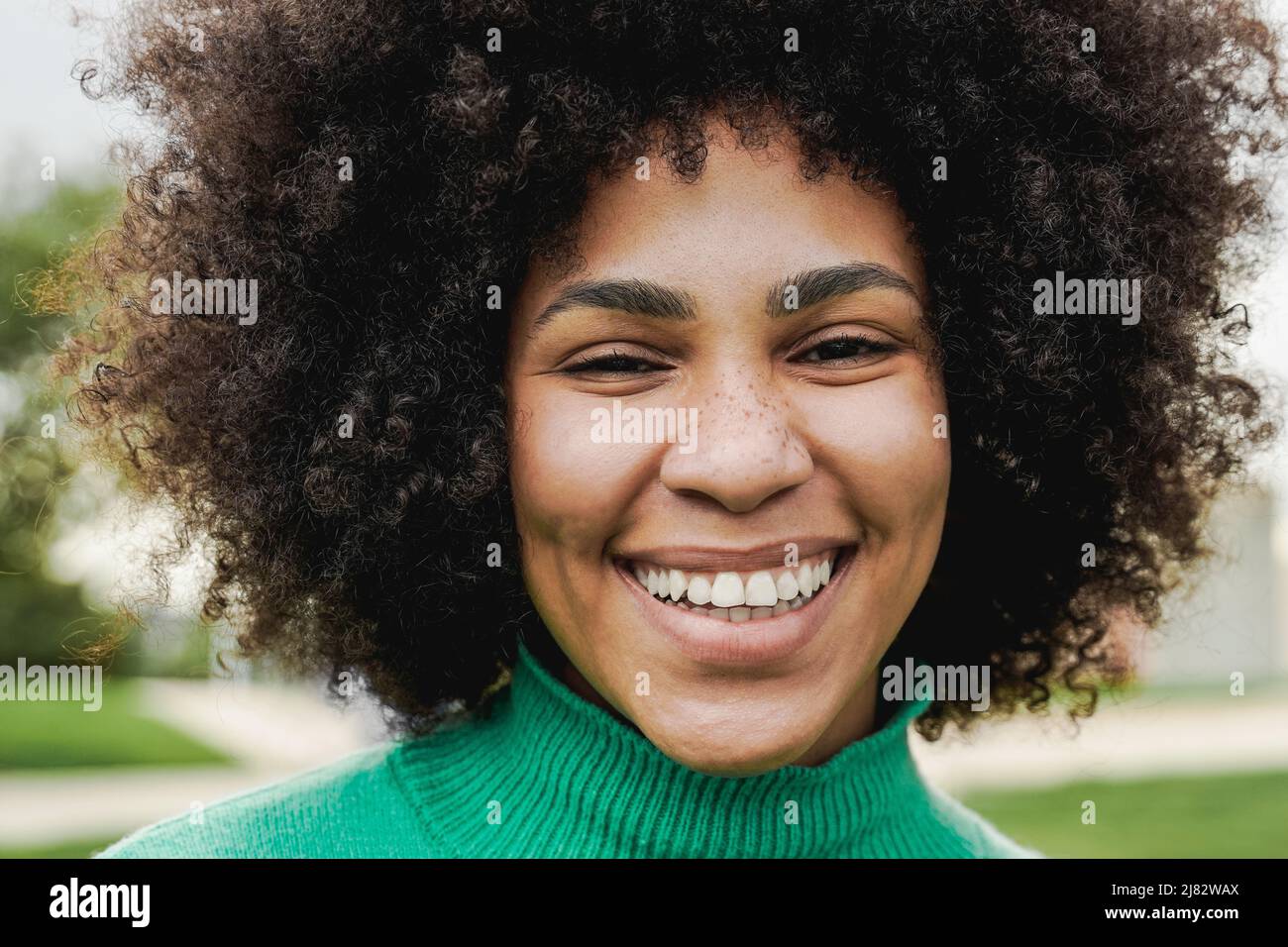 Hispanic young girl smiling and looking at camera outdoor in city park - Focus on face Stock ...