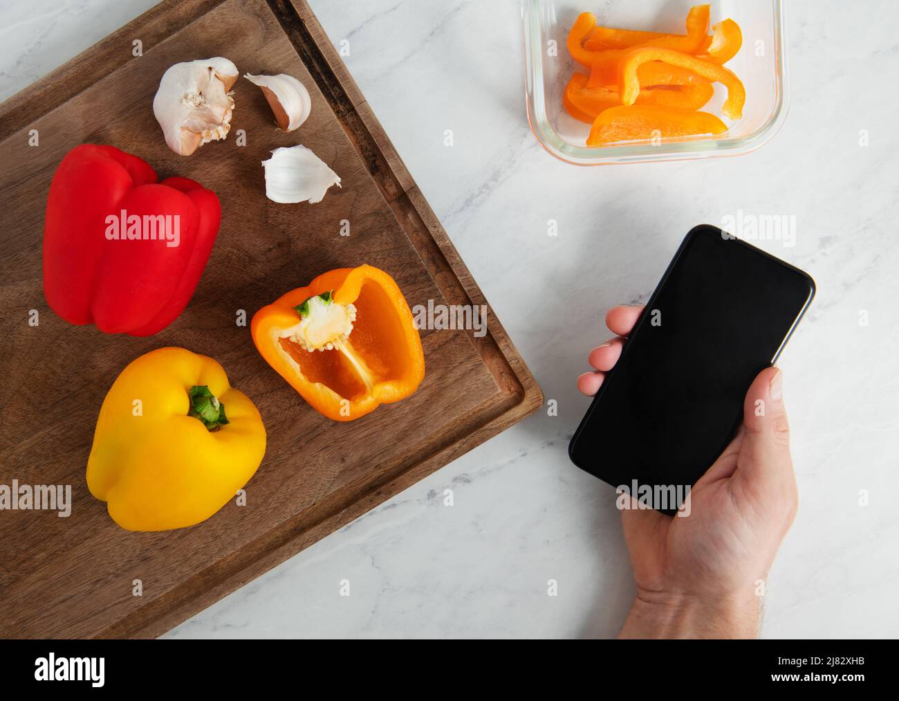 Cooking scene with peppers and garlic, and tomatoes and smart phone for ...