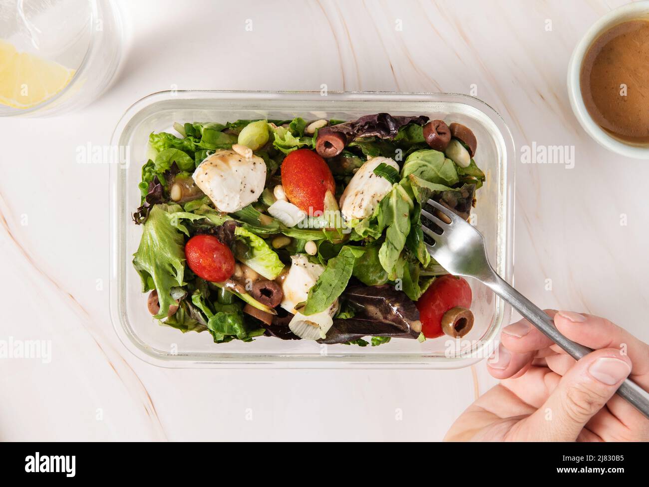 Food prep container with salad, tomato, mozzarella olives and pine nuts ...