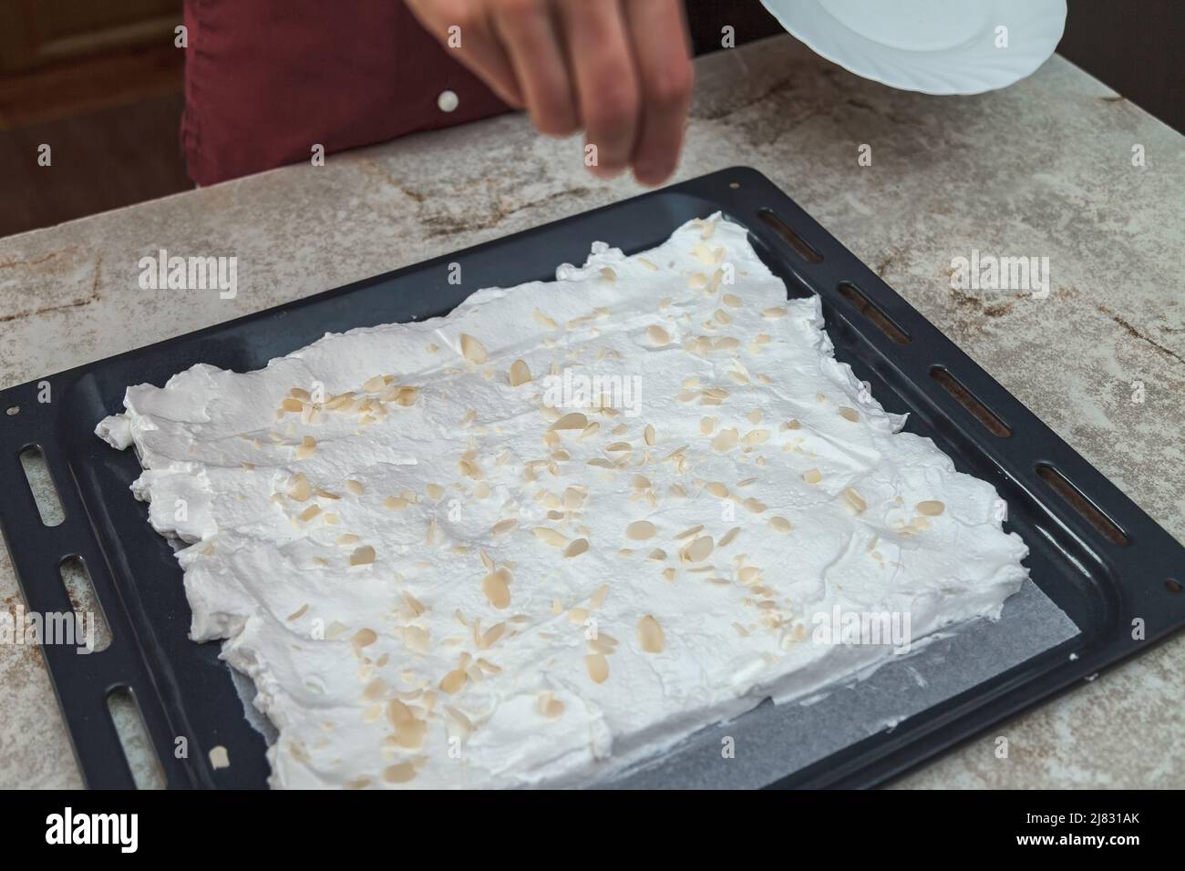 Chef Confectioner scatters almond flakes on the surface of the meringue ...