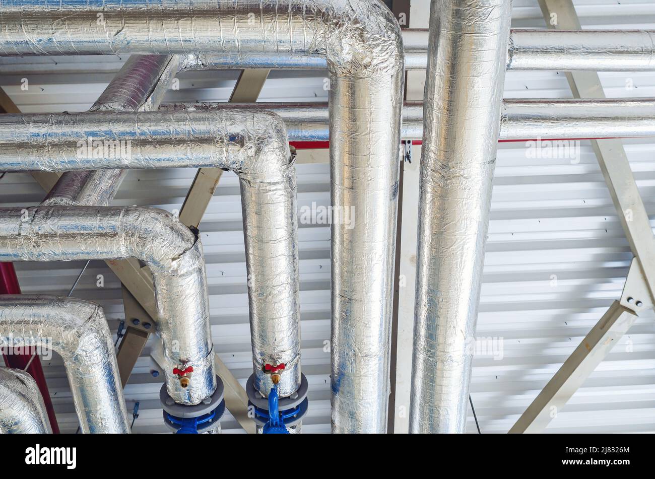 Metal pipes mounted under ceiling are covered with thermal insulation ...
