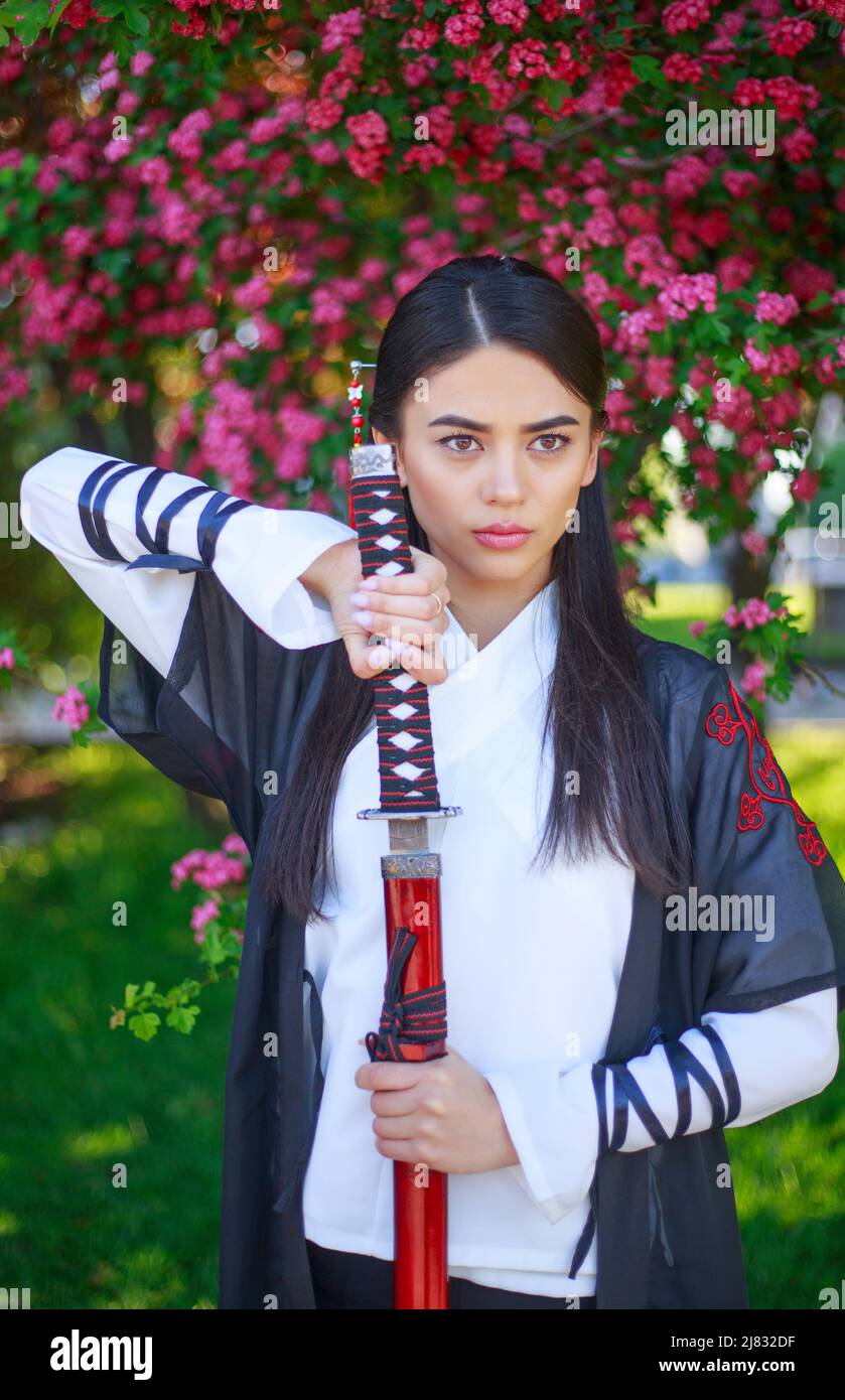 Elegant girl in a traditional kimono in a blooming flowers garden with ...