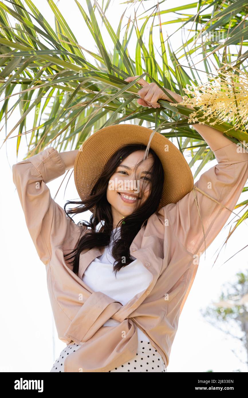 Woman standing under palm tree hi-res stock photography and images - Alamy