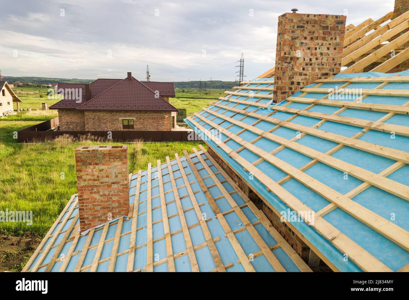 Aerial view of a brick house with wooden roof frame under construction ...