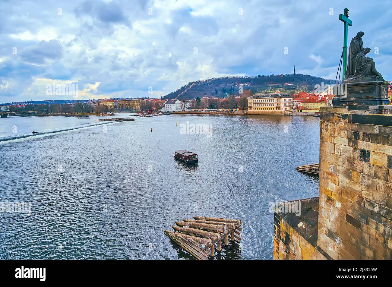 The wide Vltava River with floating boat, wooden barriers, rapids ...