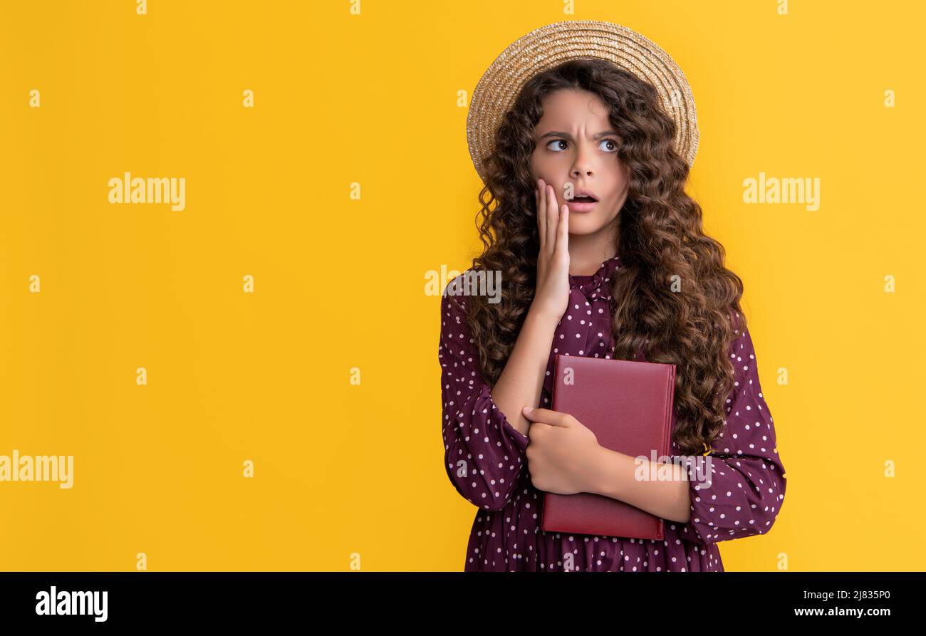 amazed kid with frizz hair hold book on yellow background Stock Photo ...
