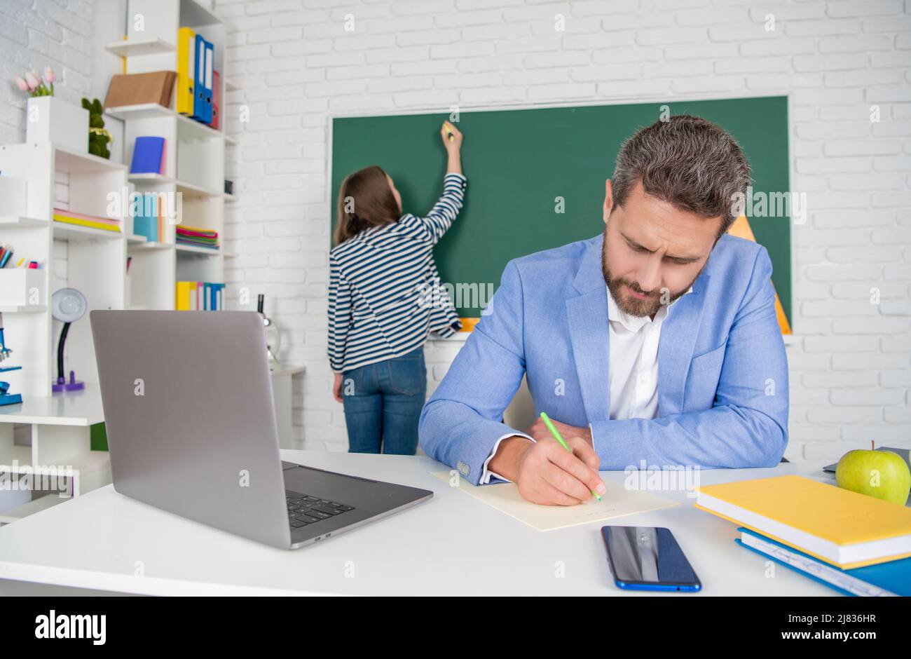 busy school teacher in classroom with selective focus of kid at ...