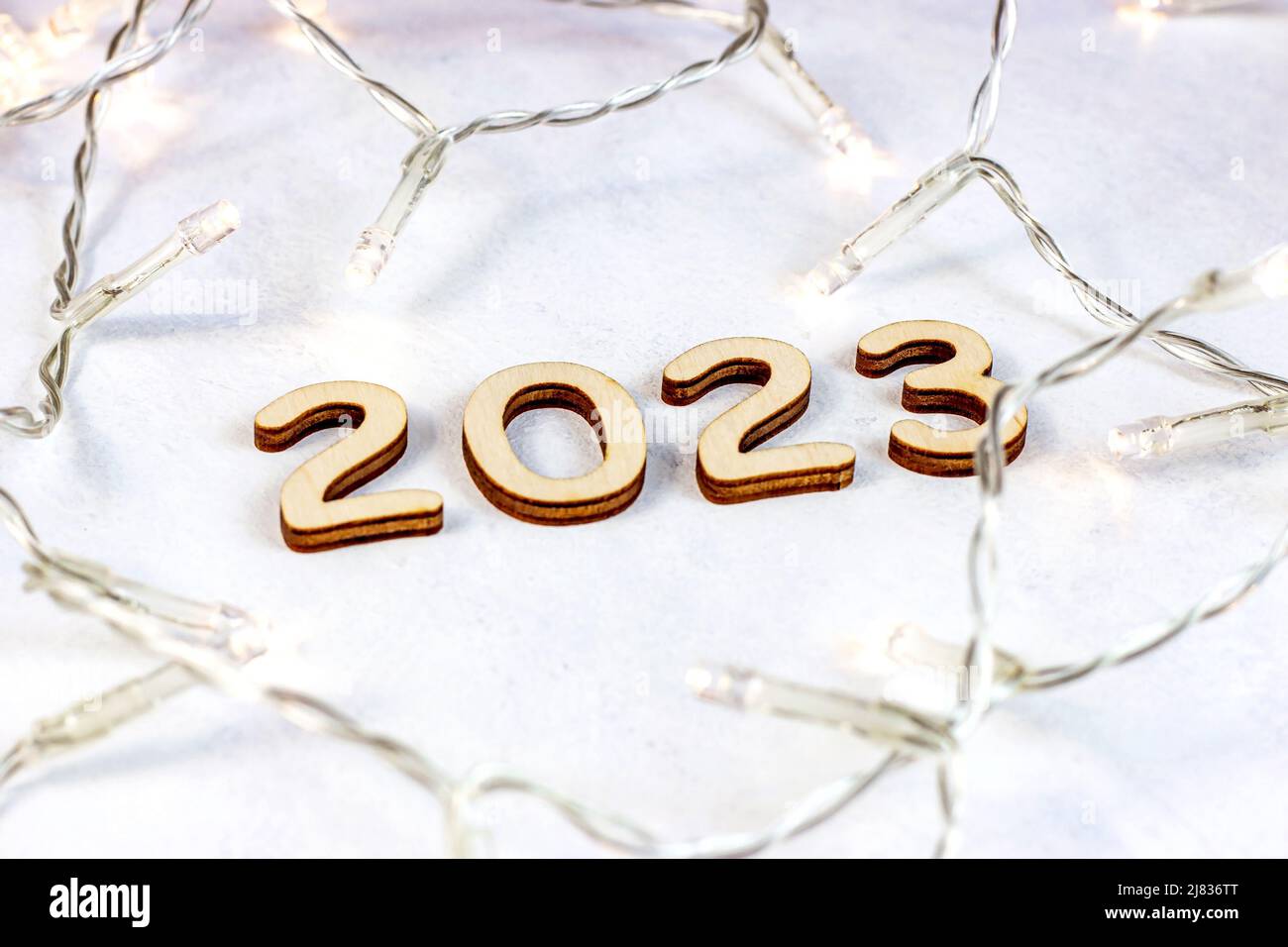 Wooden numbers 2023 silhouette with Christmas lights on light bokeh ...