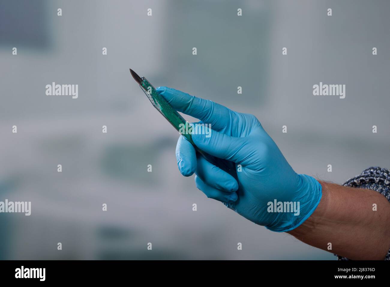 Doctor's hand with a new disposable scalpel in front of a clinic room ...