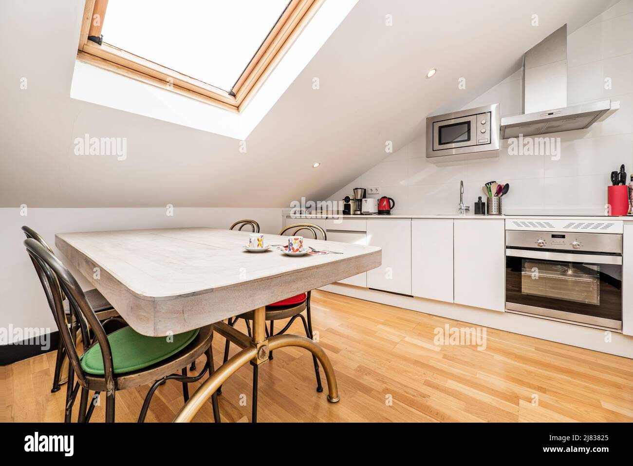 Wooden dining table with metal foot next to a kitchen with white ...