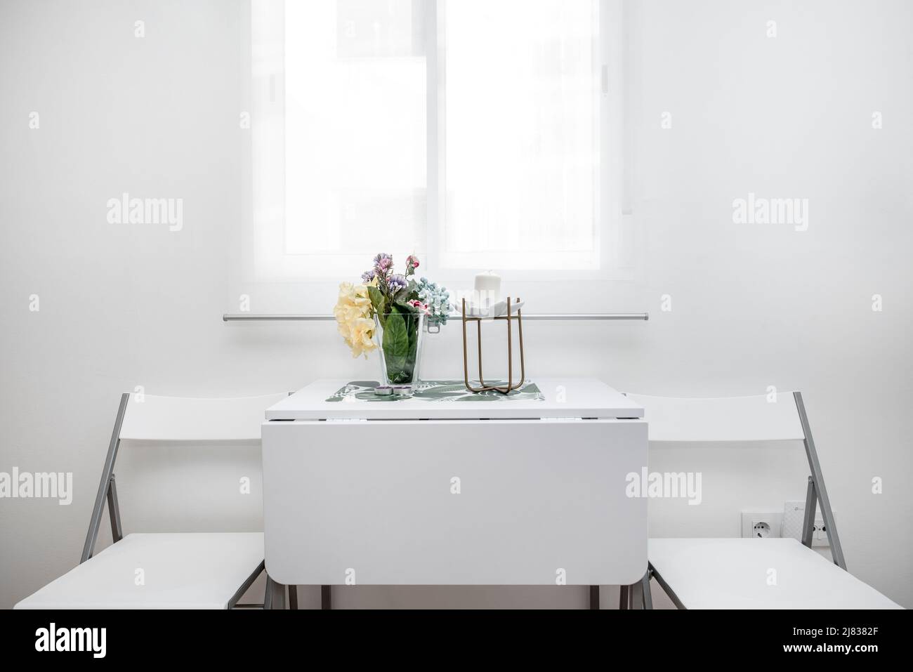White folding dining table with matching chairs below a window with a ...