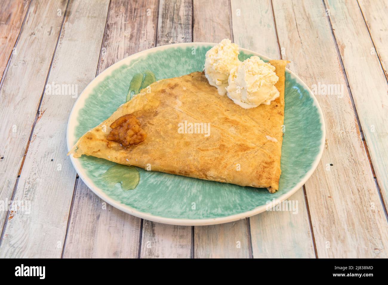 Crepe with icing sugar, vanilla ice cream and apple pie with syrup on a ...