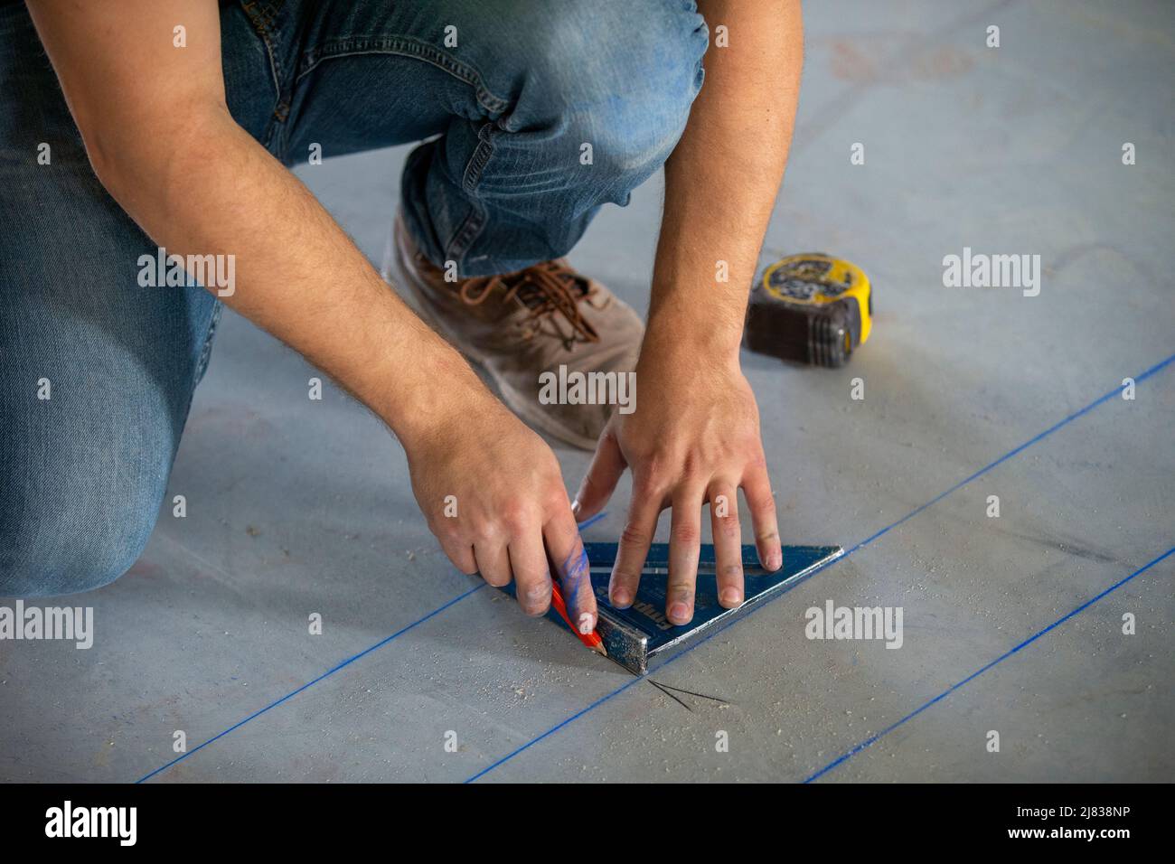Construction worker measuring and outlining the floor of an affordable ...
