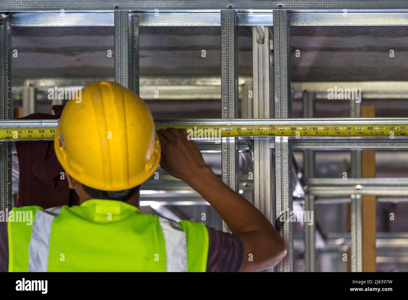 Skilled construction framer measuring space for installing another ...