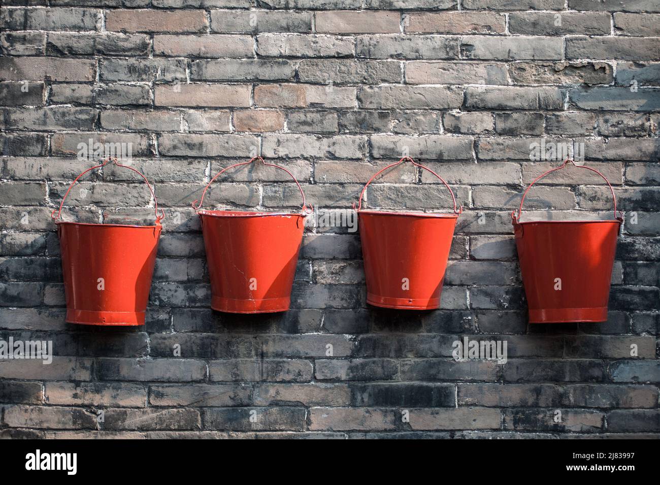 Four fire buckets hanging on the grey brick wall Stock Photo - Alamy