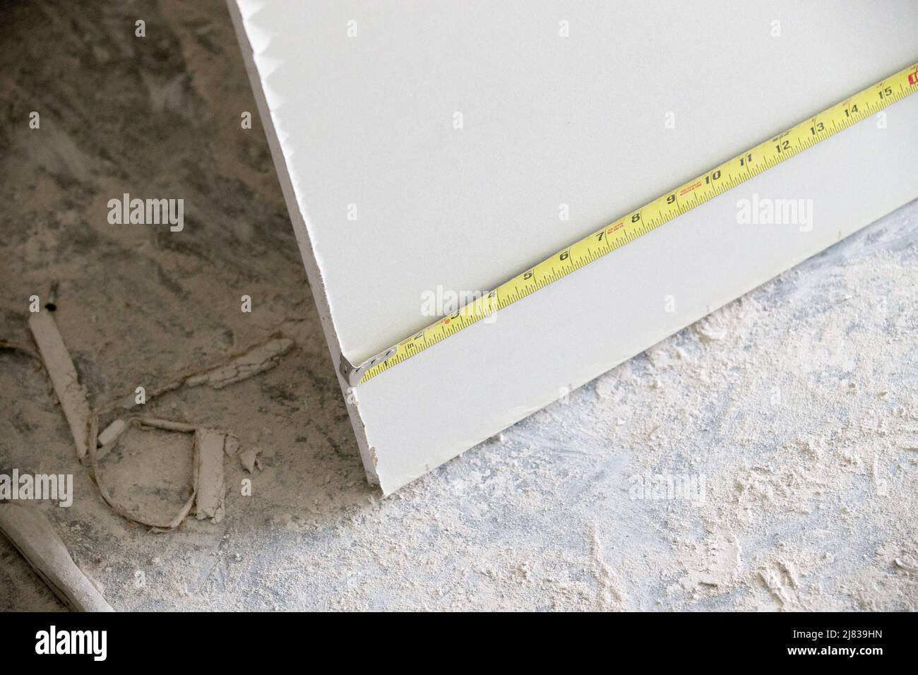 a piece of Drywall / Sheetrock is being measured for cutting and ...