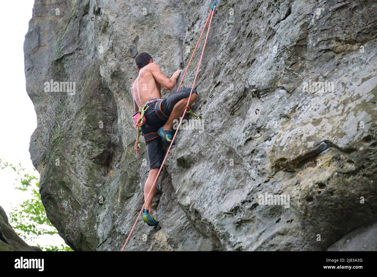 Strong male climber climbing steep wall of rocky mountain. Sportsman ...