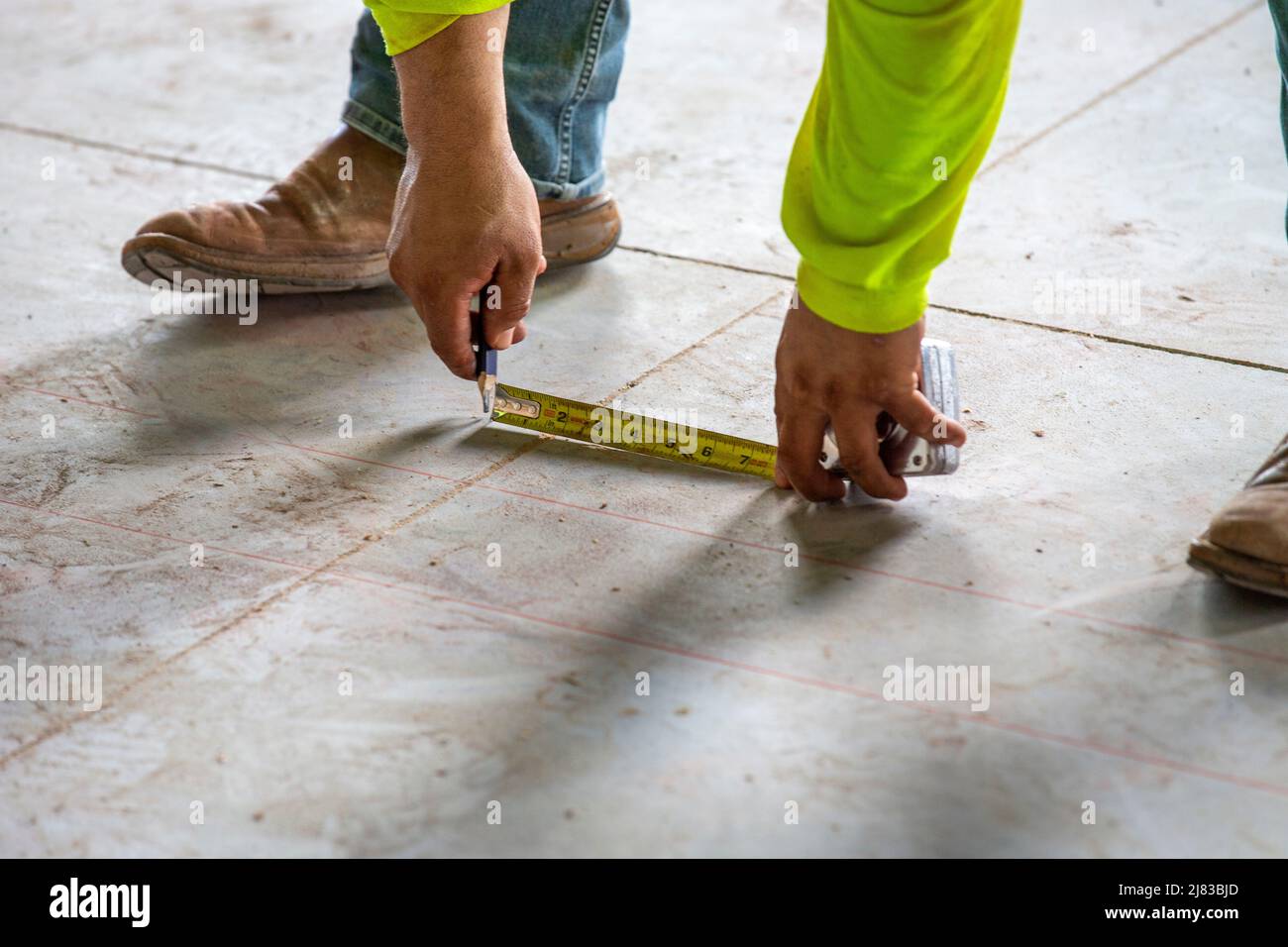 Construction worker outlines from blueprint to concrete for framing ...