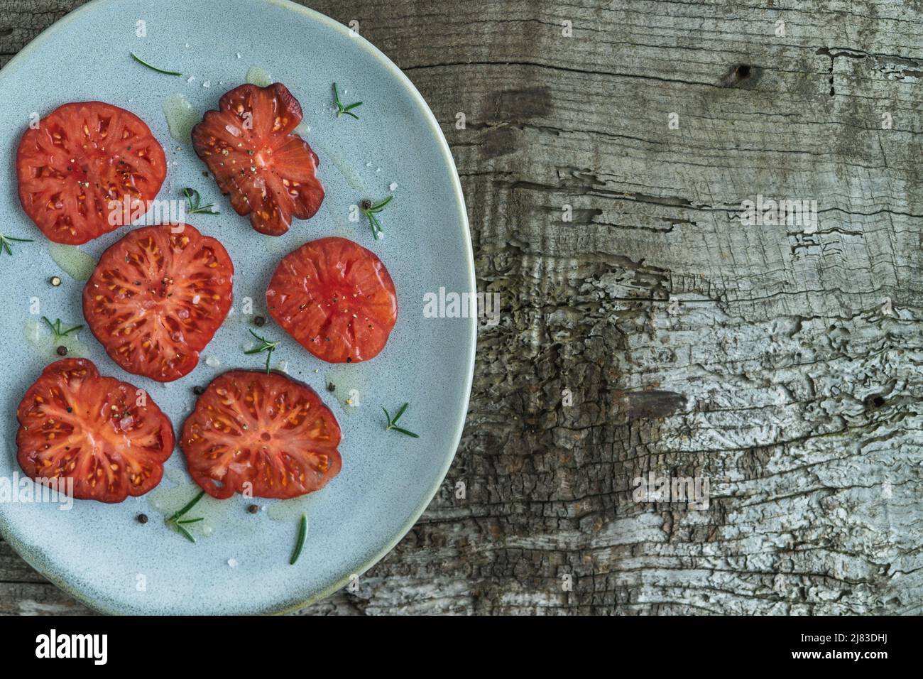 Slices of blue sea tomato with dressing on a rustic wooden plate. Top ...