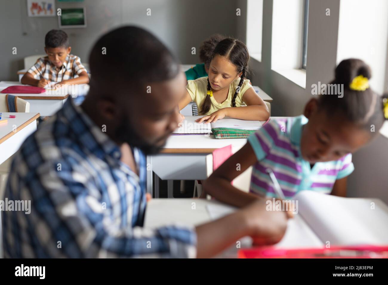 African american young male teacher assisting african american ...