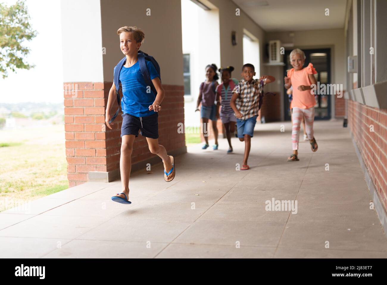 Multiracial elementary school students running in school corridor Stock ...