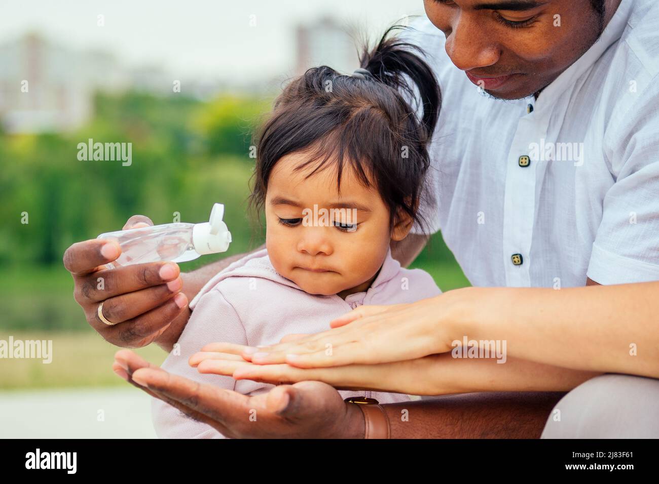 happy family applying hand-sanitizer anti-bacterial gel to daughter ...