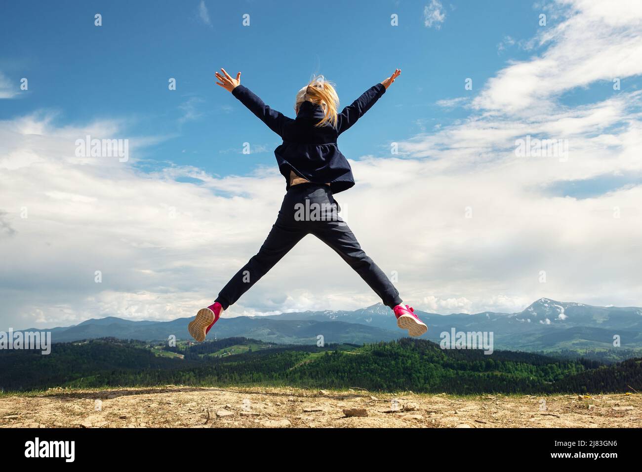 Back view of cute little blond baby girl excited kid jumping walking on ...