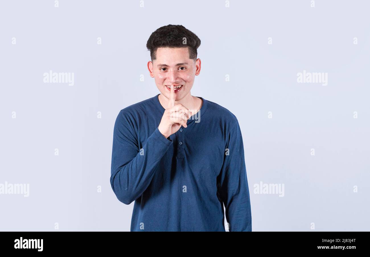 Man gesturing keep quiet, Guy smiling with finger on mouth showing hush ...