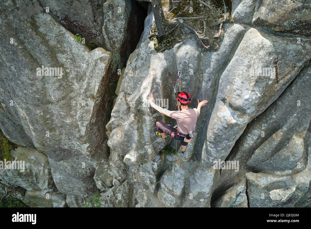 Young man climbing steep wall of rocky mountain. Male climber overcomes ...