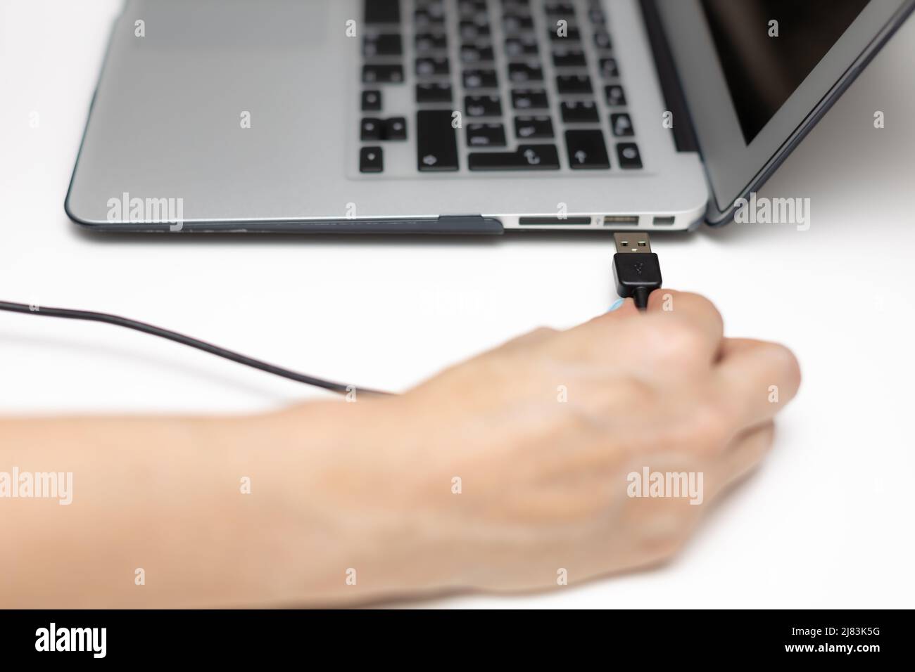 female hand inserts cable into laptop connector. High quality photo ...