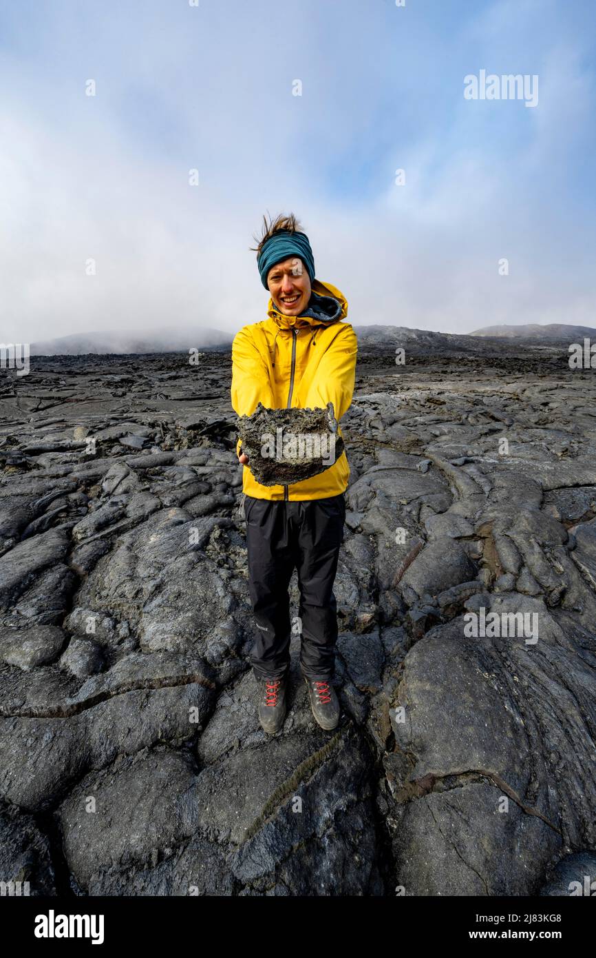 Tourist standing on petrified lava, holding lava stones in hand ...