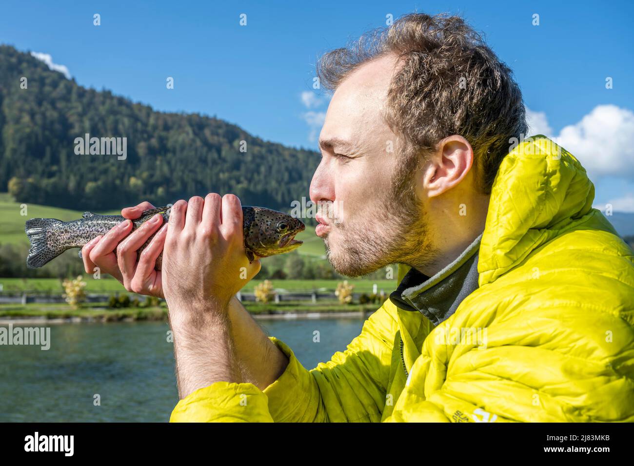 Man kisses caught trout, Proud and happy angler Stock Photo - Alamy