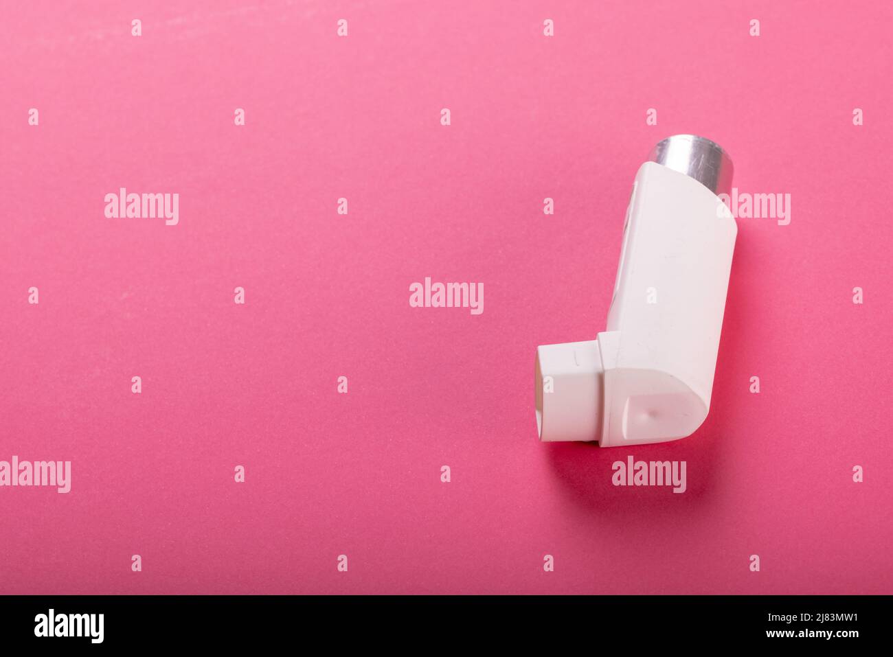 High angle view of white asthma inhaler isolated against pink ...