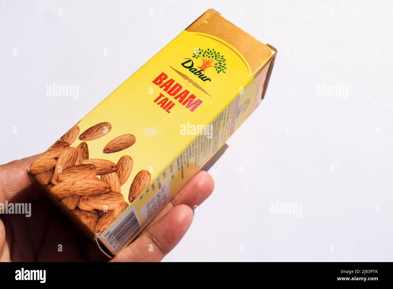 Hands holding Dabur Pure Almond oil or Badam tail box bottle packet in ...