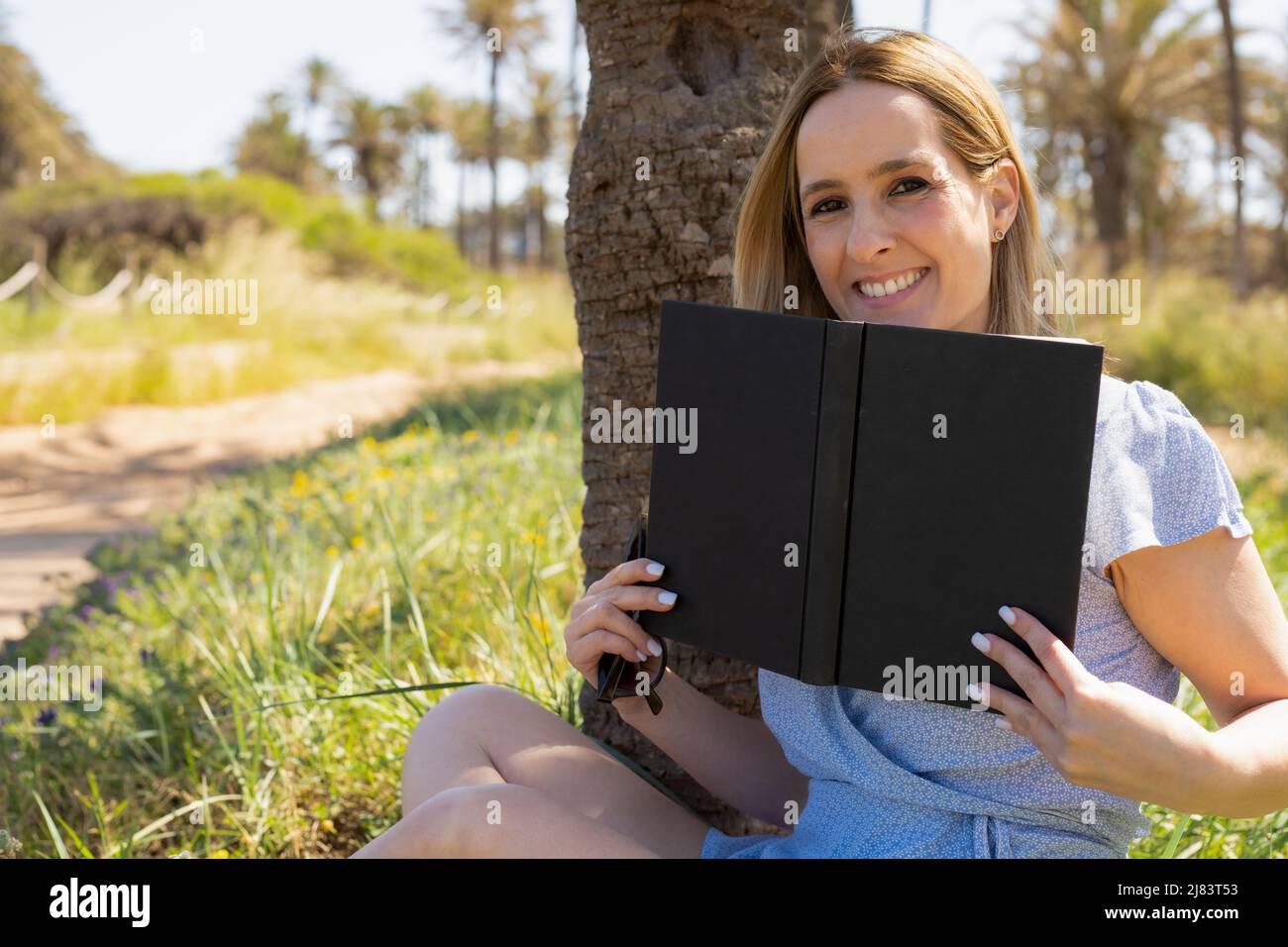 Young smiling woman reading a book in a park outdoors Stock Photo - Alamy