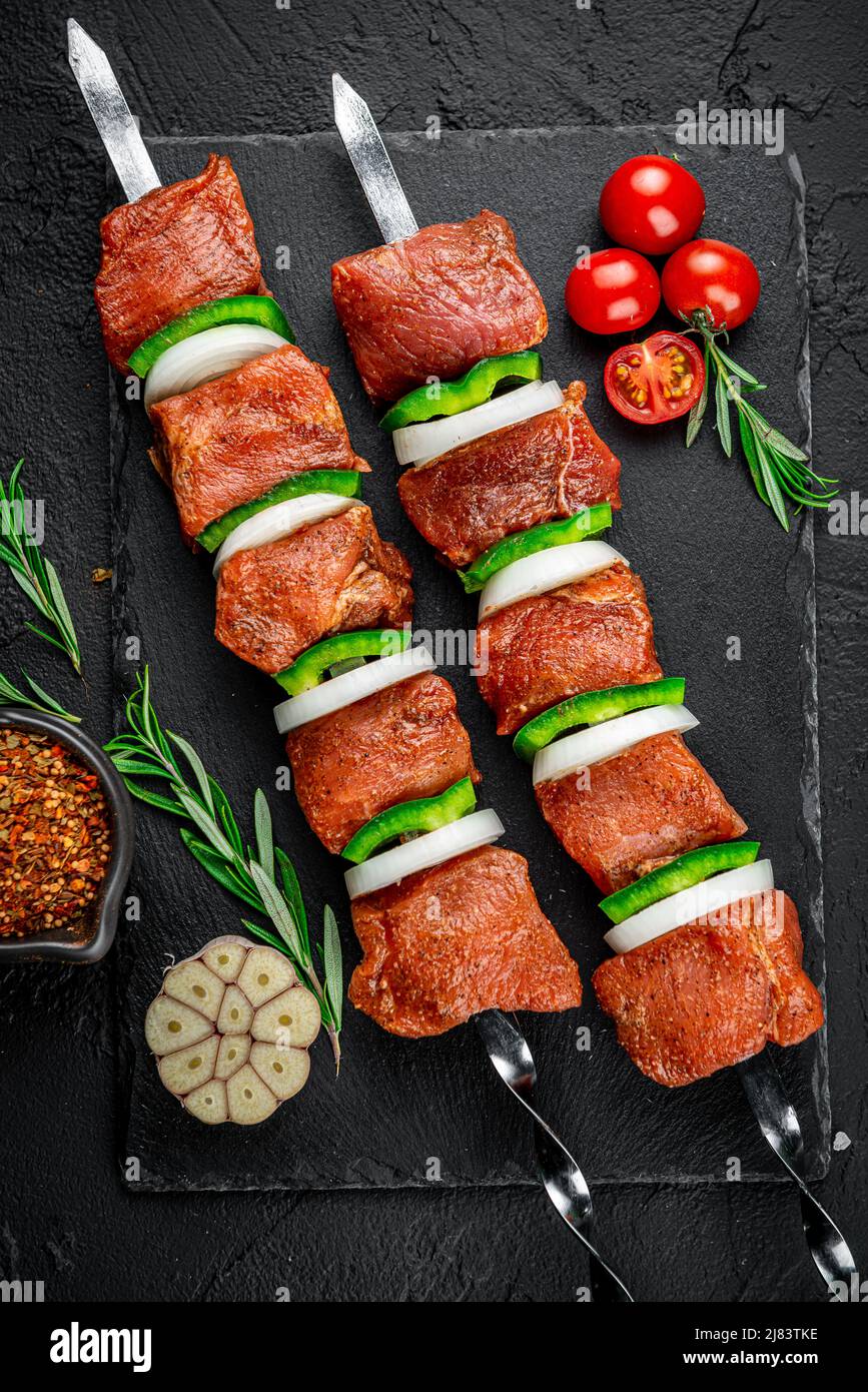 raw kebab with vegetables. On a black stone background Stock Photo - Alamy