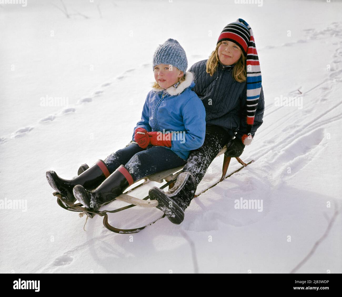 1960s TWO GIRLS ROSY CHEEK SISTERS RIDING LOOKING UP ON SLED TOGETHER ...